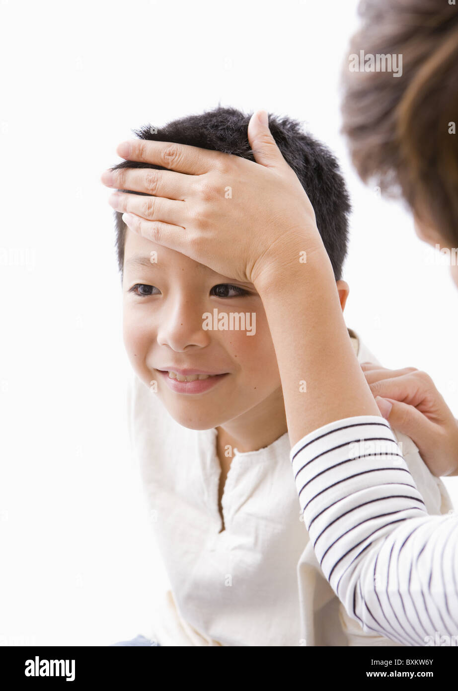 Mother placing her hand on her son's forehead Stock Photo - Alamy