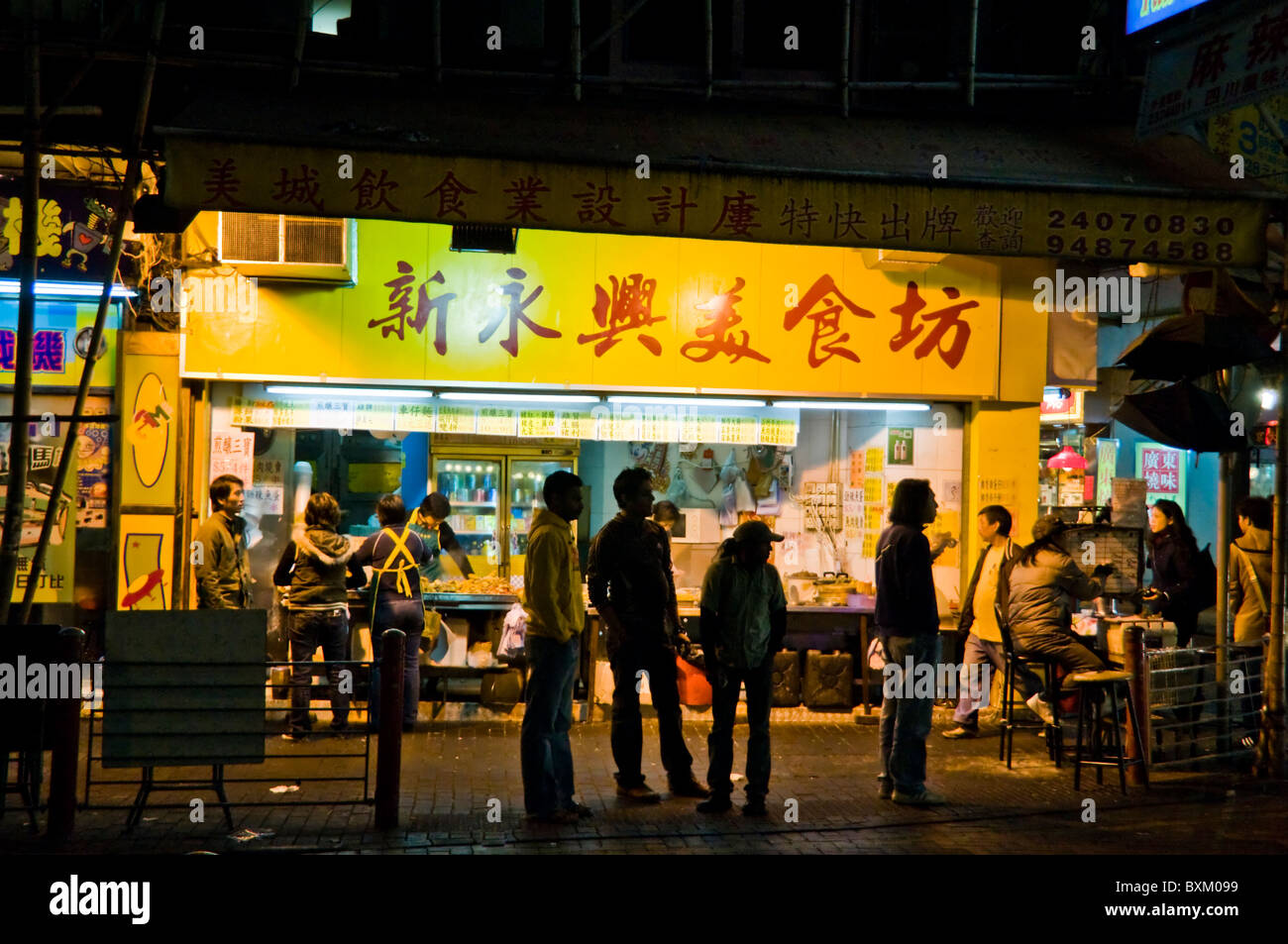 Young oriental people standing on street corner outside store in ...