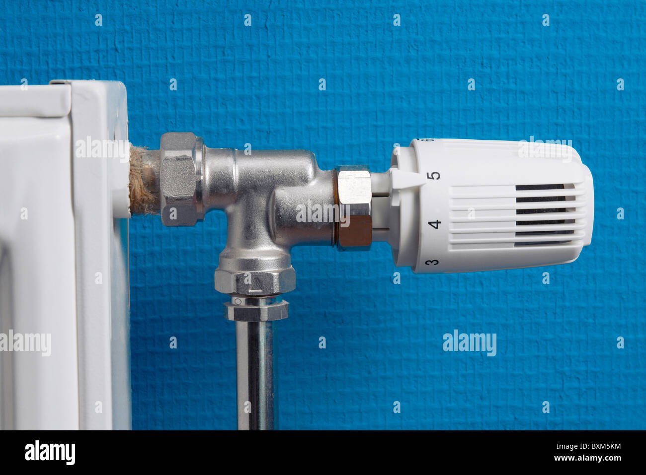 Heating radiator with regulator in front of blue wall Stock Photo - Alamy