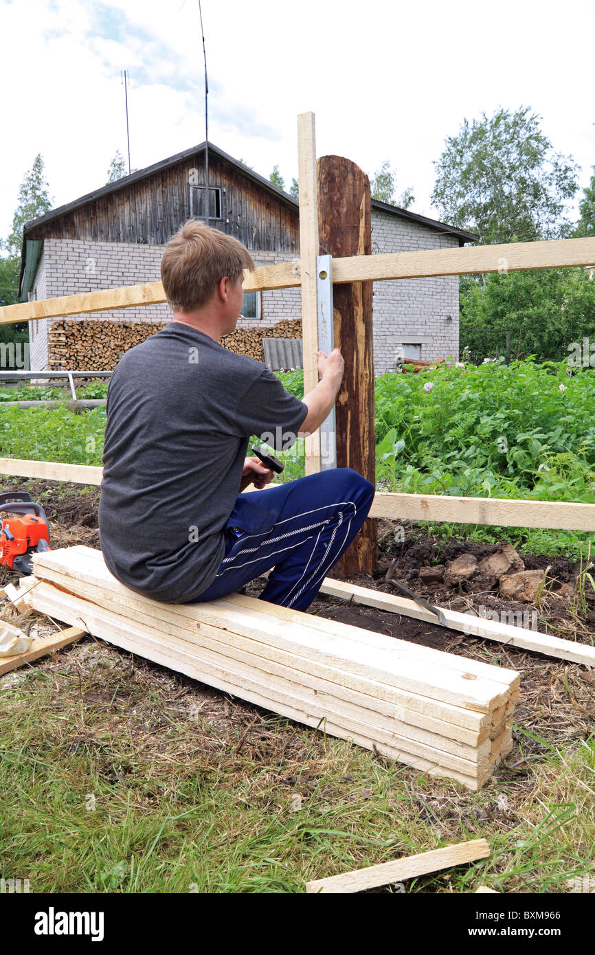 man builds fence Stock Photo - Alamy