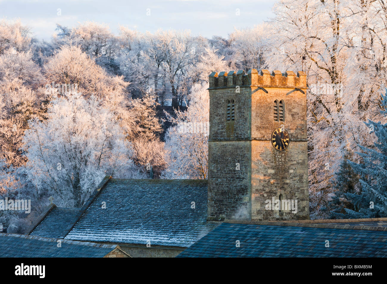 The sun setting on St Andrews church in the hoar frost covered Cotswold ...