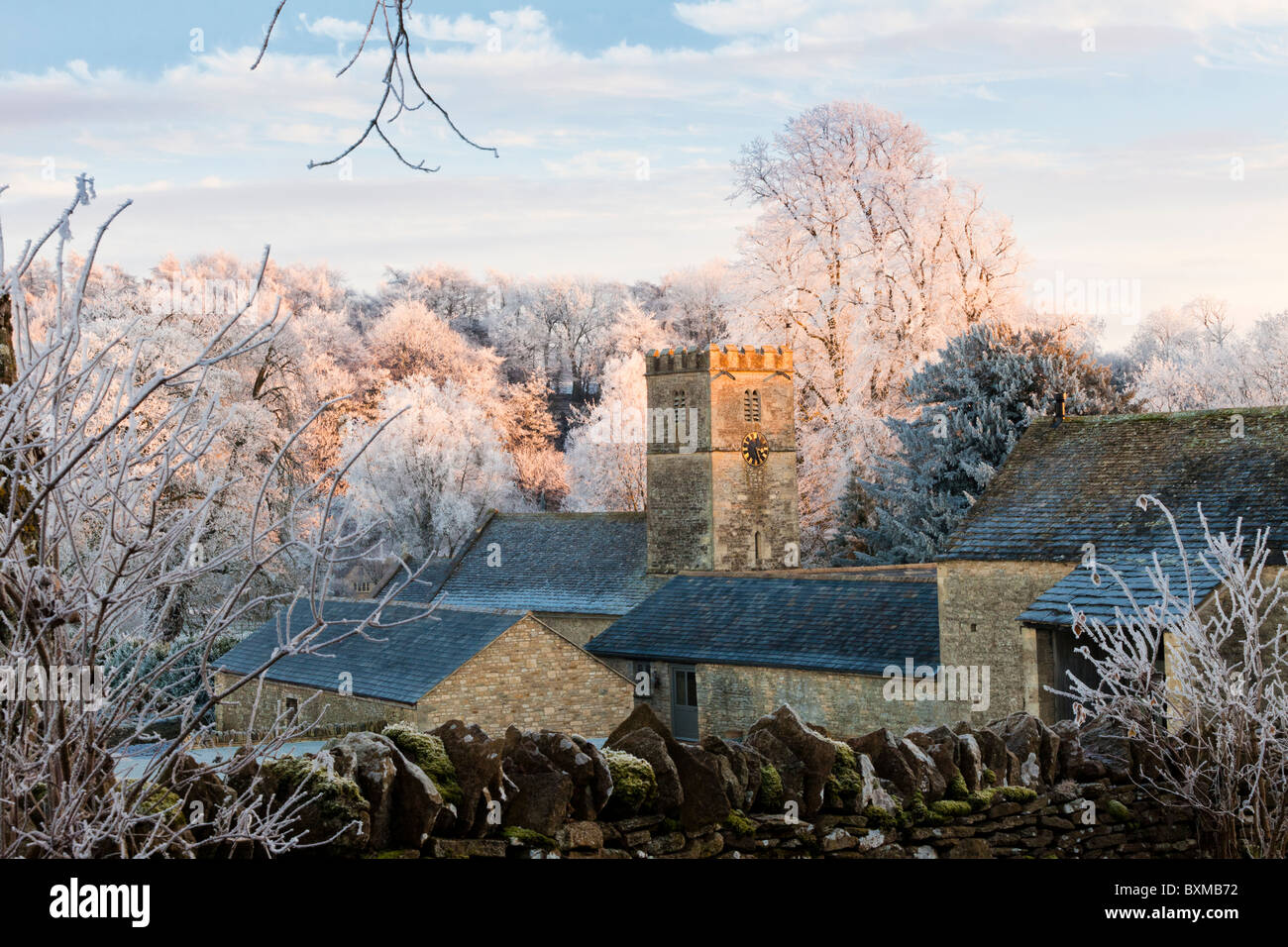 The sun setting on St Andrews church in the hoar frost covered Cotswold ...
