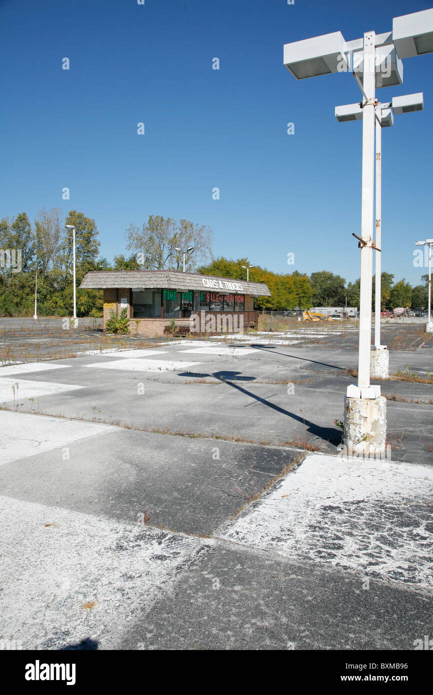 Empty abandoned car and truck dealer lot with weeds growing. Sign reads ...