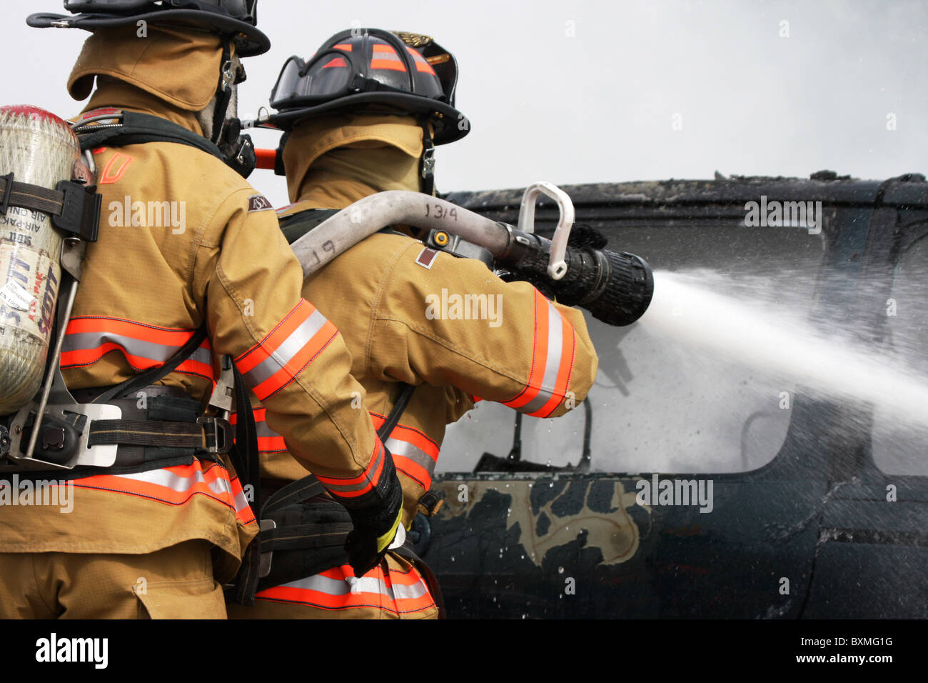 Firefighters on a hoseline fighting a car fire Stock Photo - Alamy
