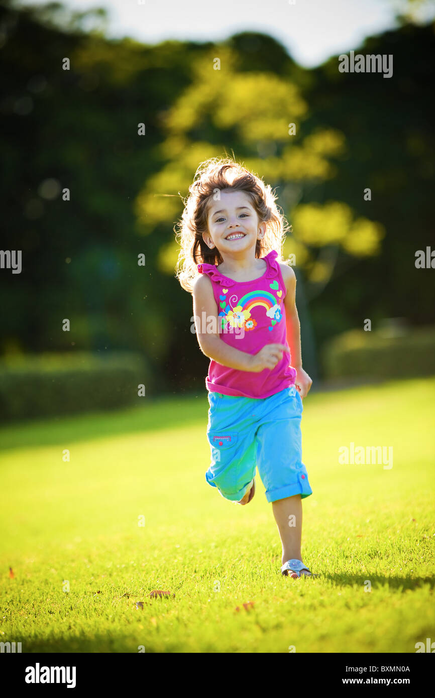 Young excited and smiling girl running in the sunlit grass Stock Photo ...