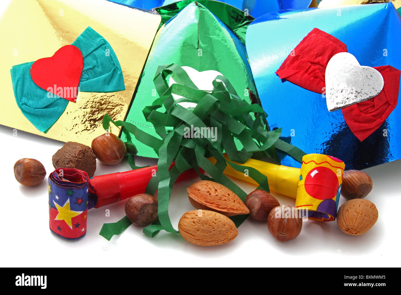 Mixed nuts with party blowers and hats on a plain white background ...