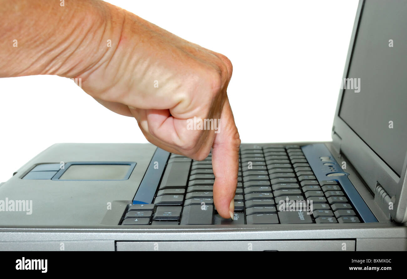 A forefinger of a hand hitting the enter button on a laptop computer ...