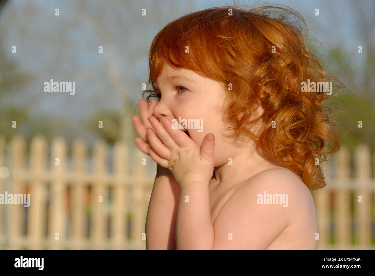 A small female child playing a game of peek a boo. She is laughing and ...