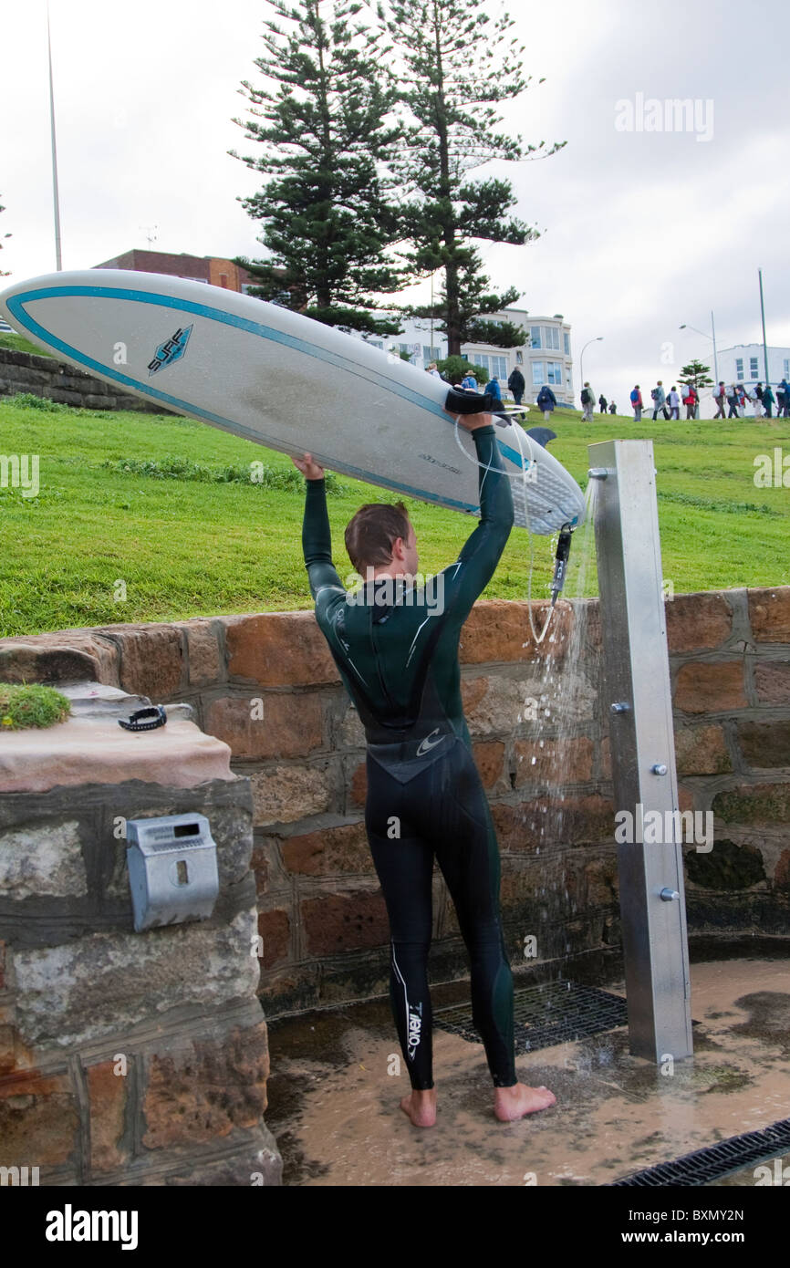 Young man rinsing surfboard off under the shower at Bondi Beach Stock ...