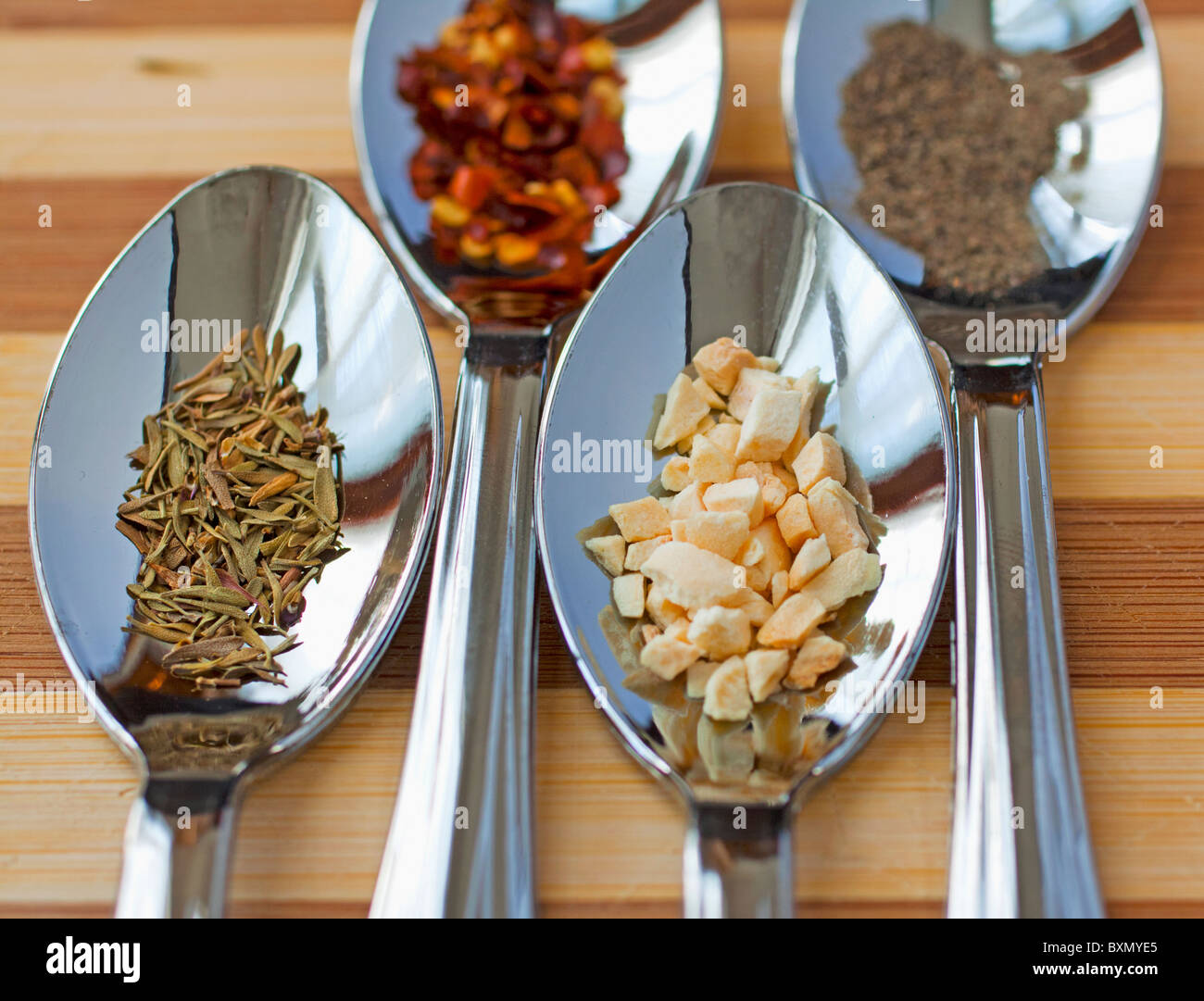 Four different spices (chilli, pepper, thyme, garlic) over four metal ...