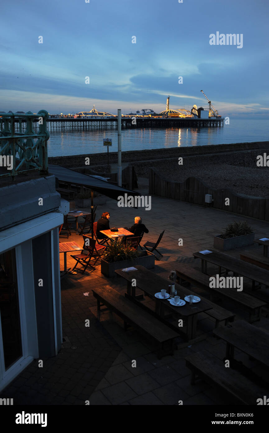 Couple sitting at seafront cafe bar at dusk by the Palace Pier in ...