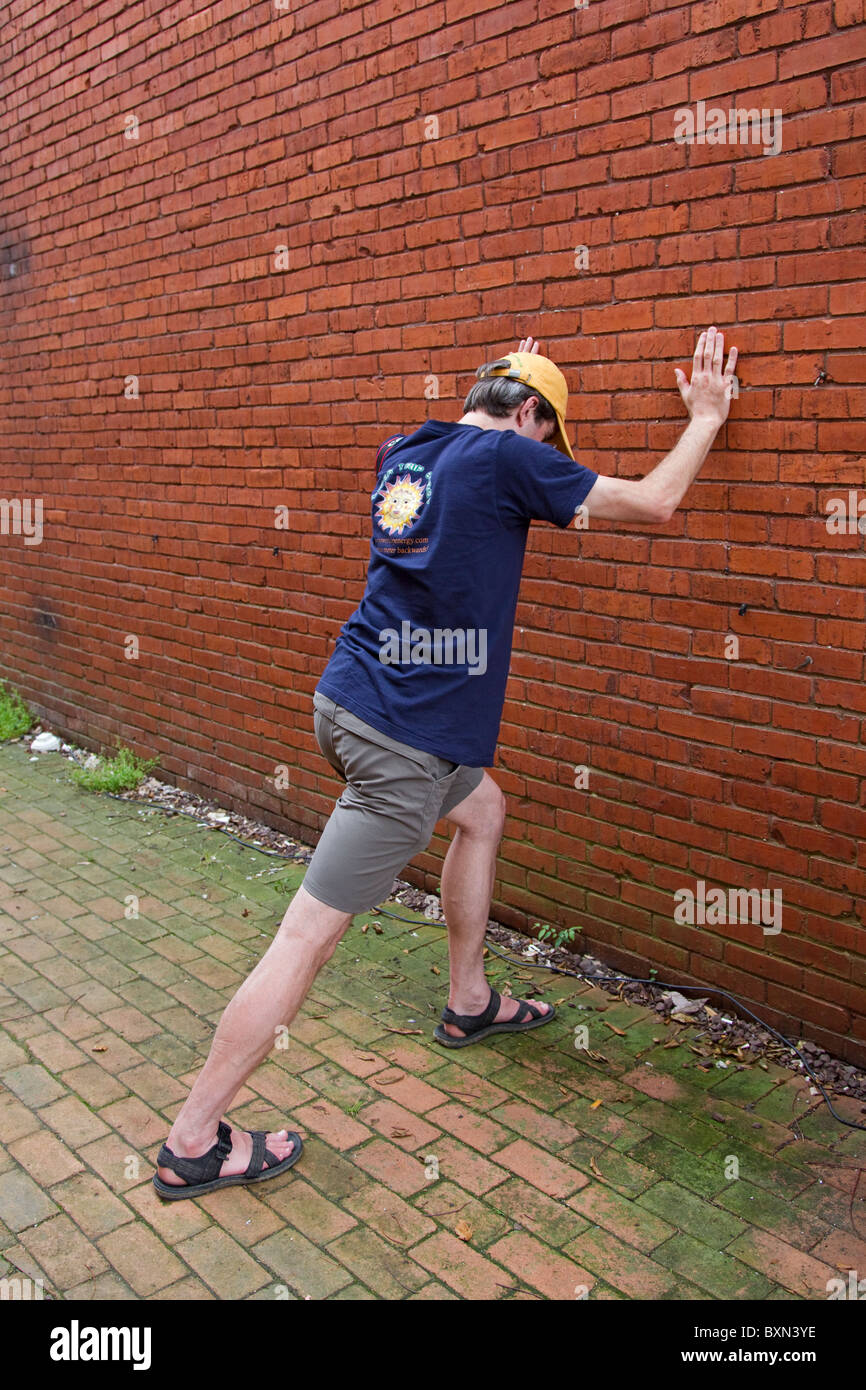 Man stretches against red brick wall Stock Photo - Alamy