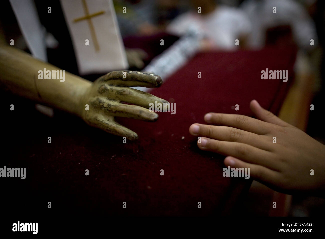 A woman touches the hand of a statue of Jesus Christ during holy week ...