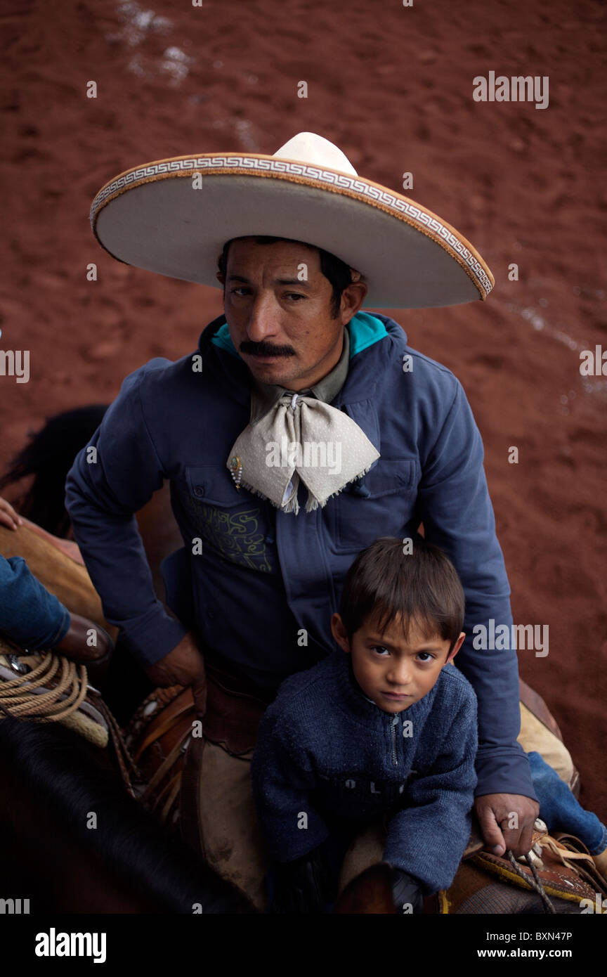 A Mexican Charro with his son rides a horse after a Charreria ...