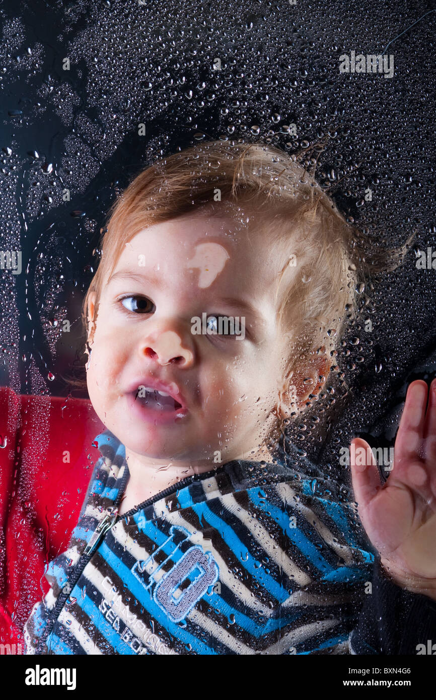 Little boy playing with condensation on window Stock Photo - Alamy