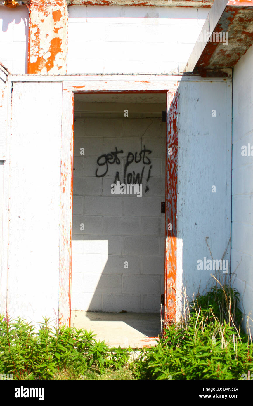 Doorway with "get out now" warning Stock Photo - Alamy