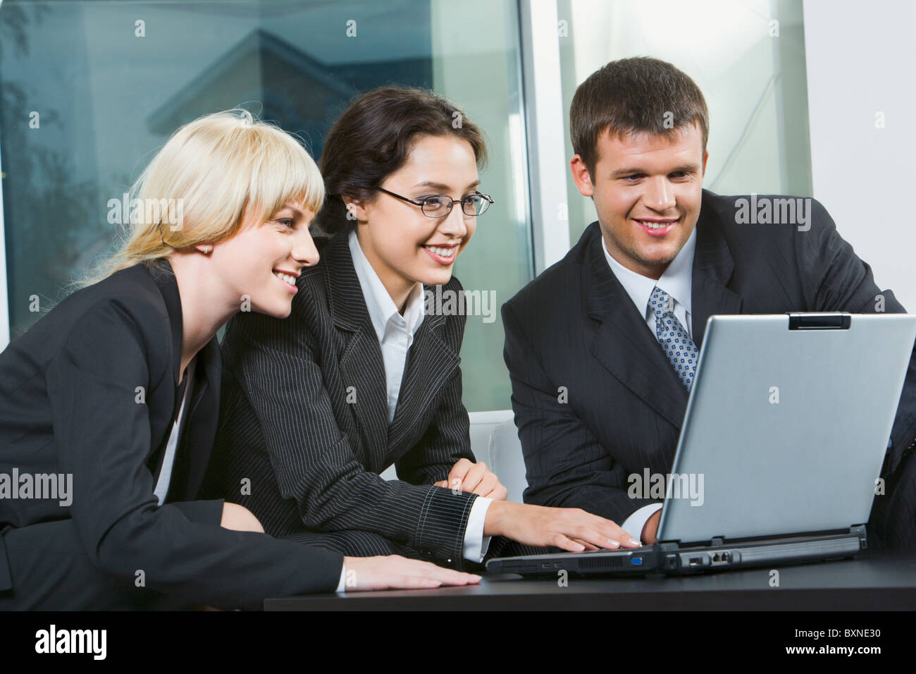 Group of three business people looking at monitor Stock Photo - Alamy