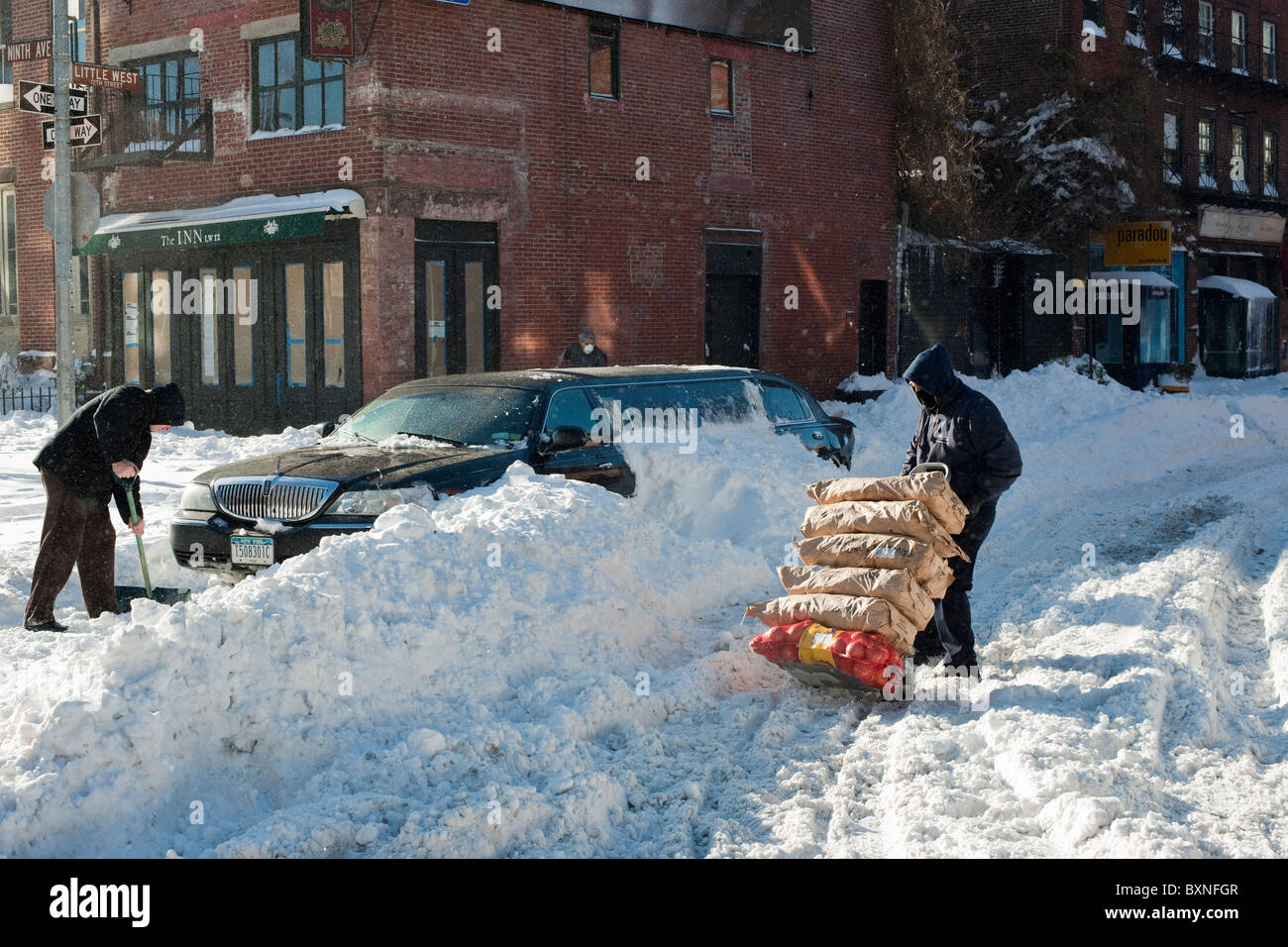 A worker struggles to make his delivery as a limo driver digs out of ...