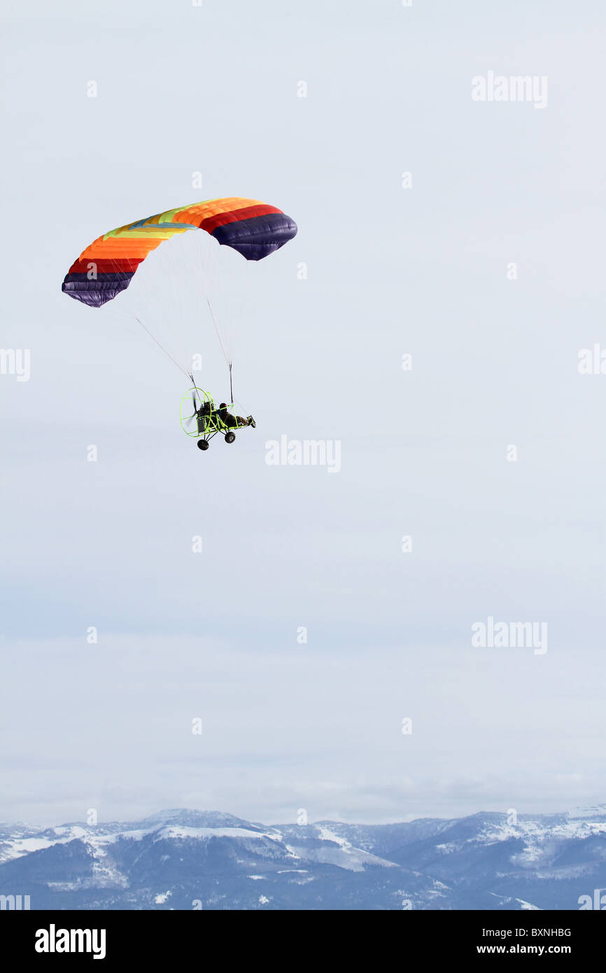 Powered parachute flight over ice and snow covered mountain in winter ...