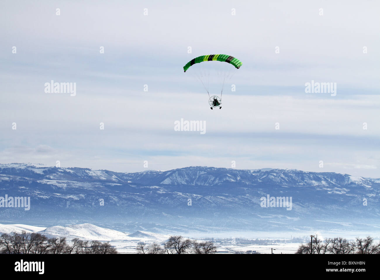 Powered parachute flying over ice and snow covered mountain in winter ...