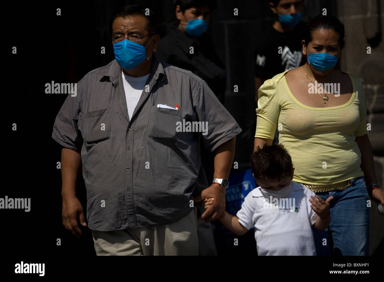 A family wearing masks as a precaution against swine flu walks in ...