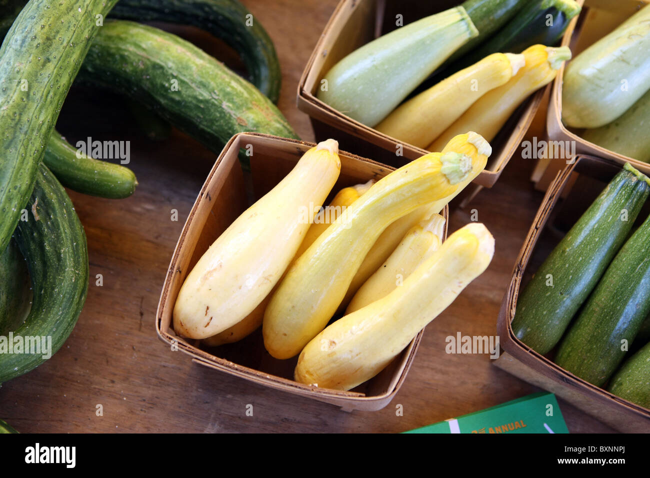 Yellow squash rests among cucumbers and zucchini at the local farmers ...
