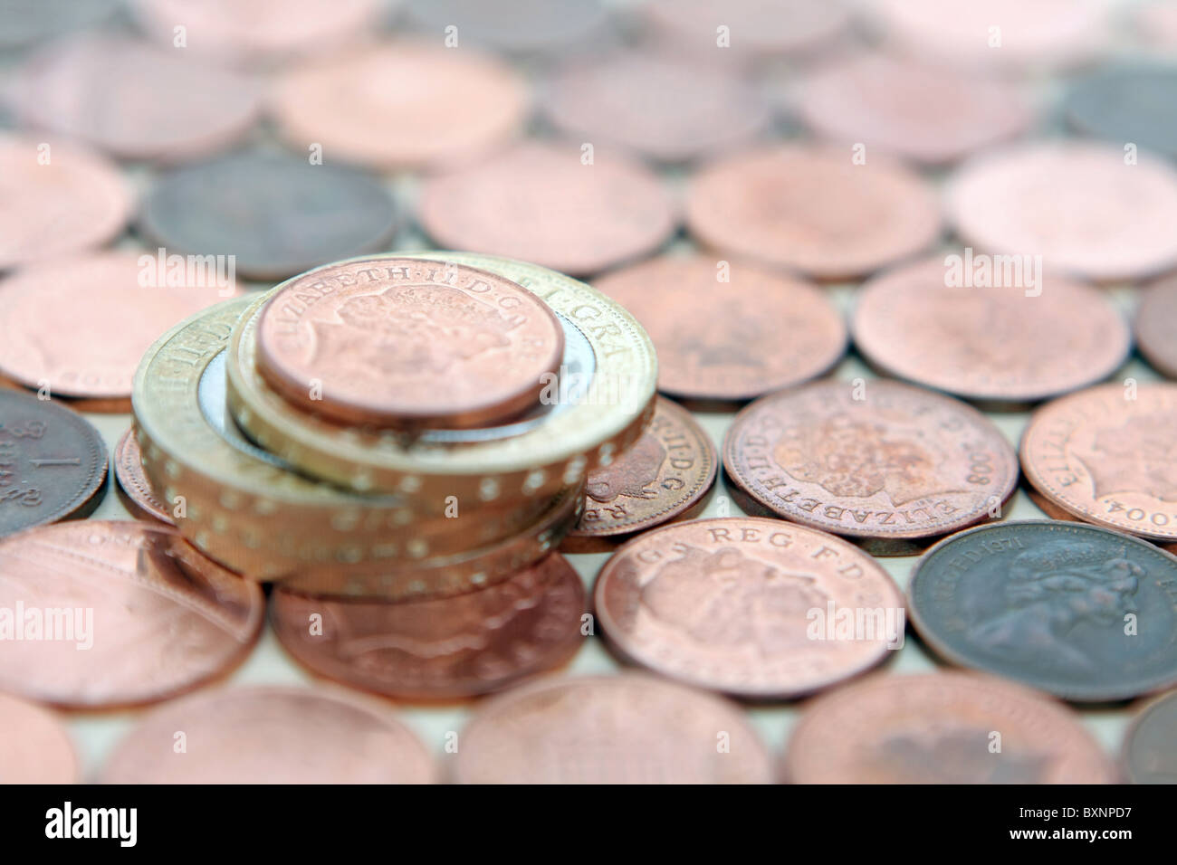 A sterling 1p coin on a stack of £2 coins - all on a background of 1p ...