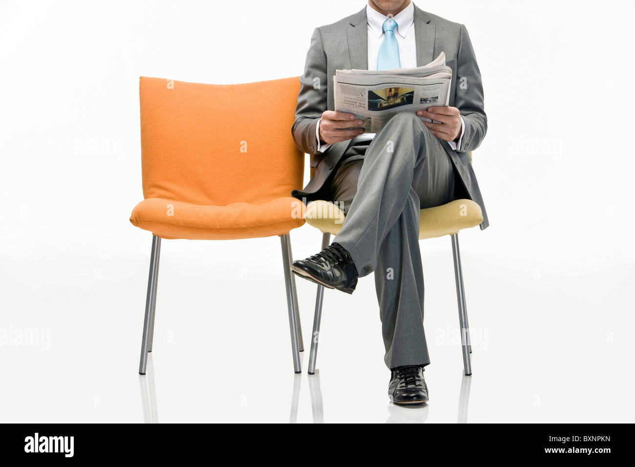 Businessman reading newspaper, sitting on chair Stock Photo - Alamy