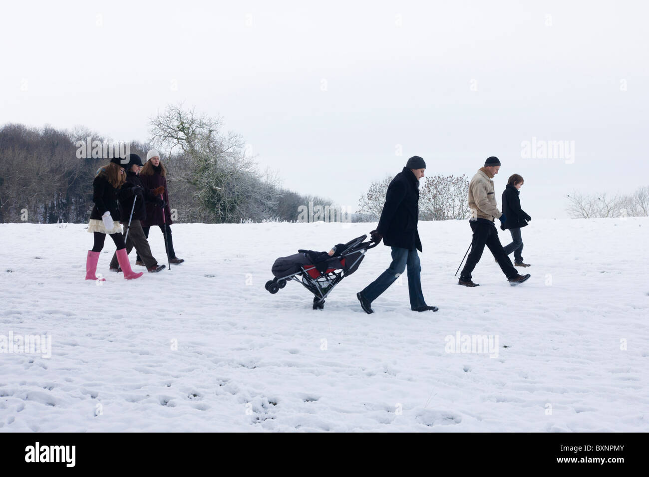 Dragging a baby's buggy as family members go out for a walk on open ...