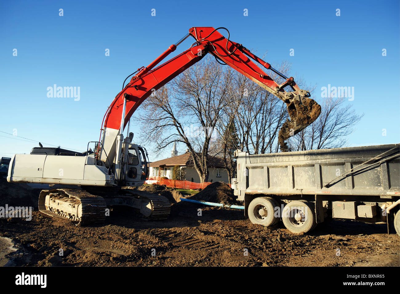 Construction: Red mechanical digger and truck at work excavating a ...