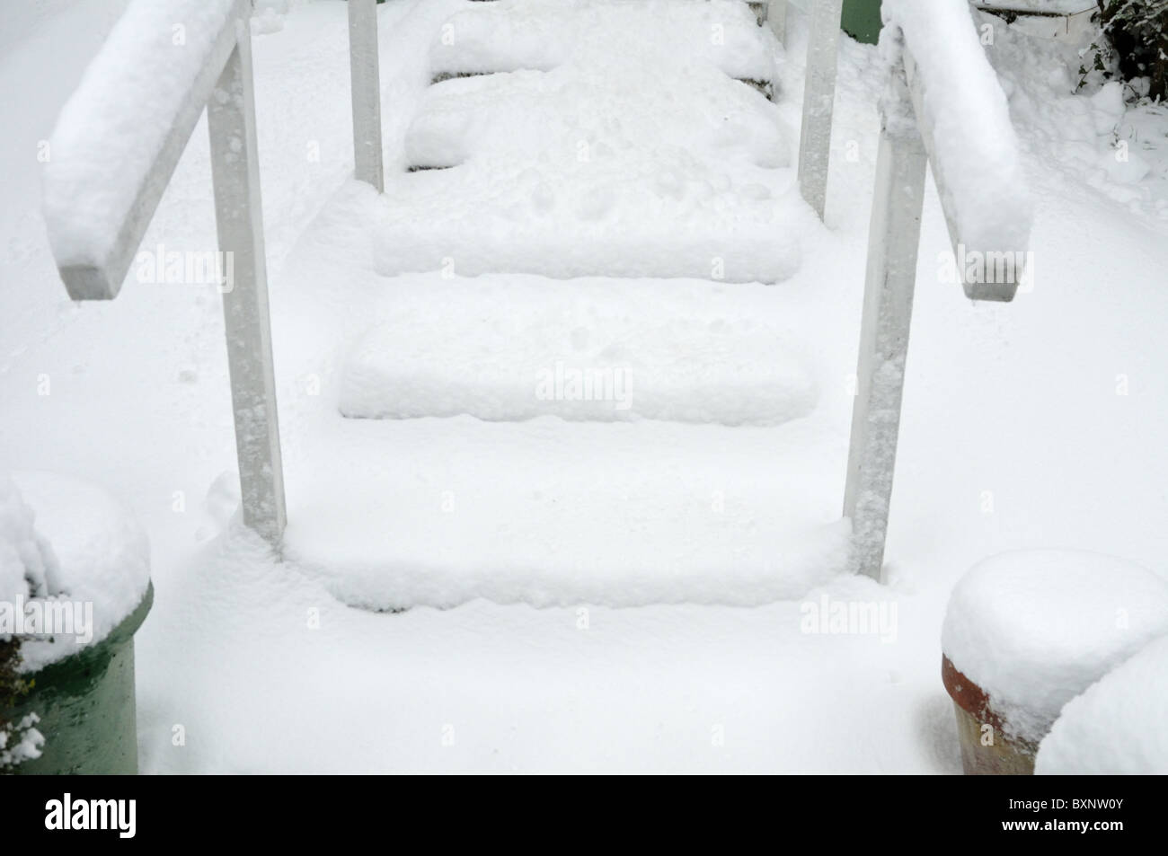 Snow covered wooden handrails on steps leading up to a suburban house ...