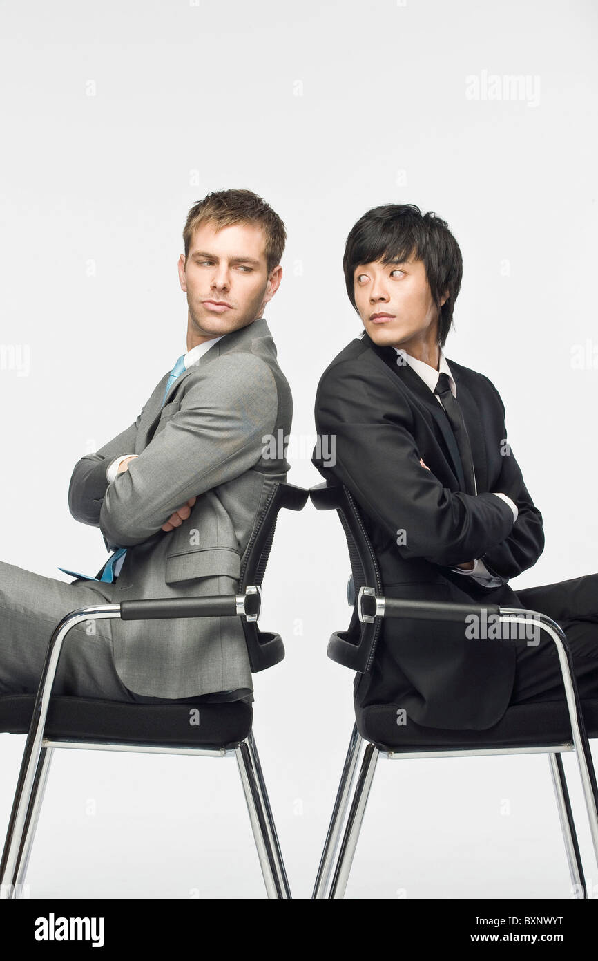 Two businessman sitting back to back, side view Stock Photo - Alamy