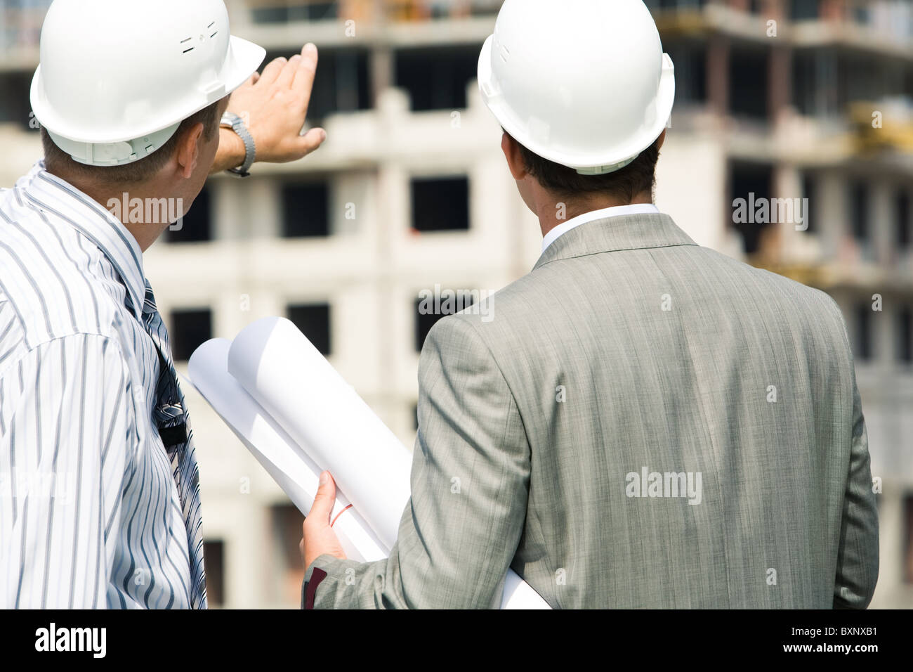 Photo of backs of workers interacting and looking at building Stock ...