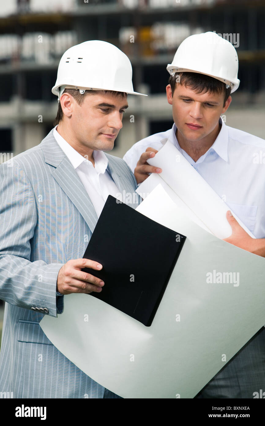 Portrait of business partners looking at new construction plan and ...