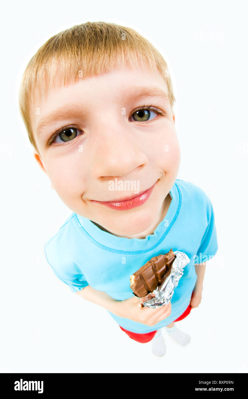 Close-up of happy boy’s face from above looking at camera and eating ...
