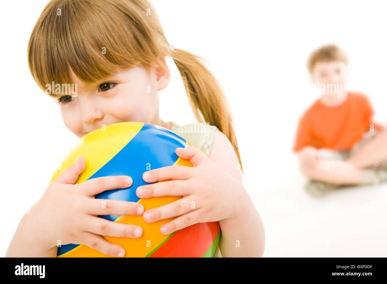 Photo of little girl holding colorful ball in hands with her brother at ...