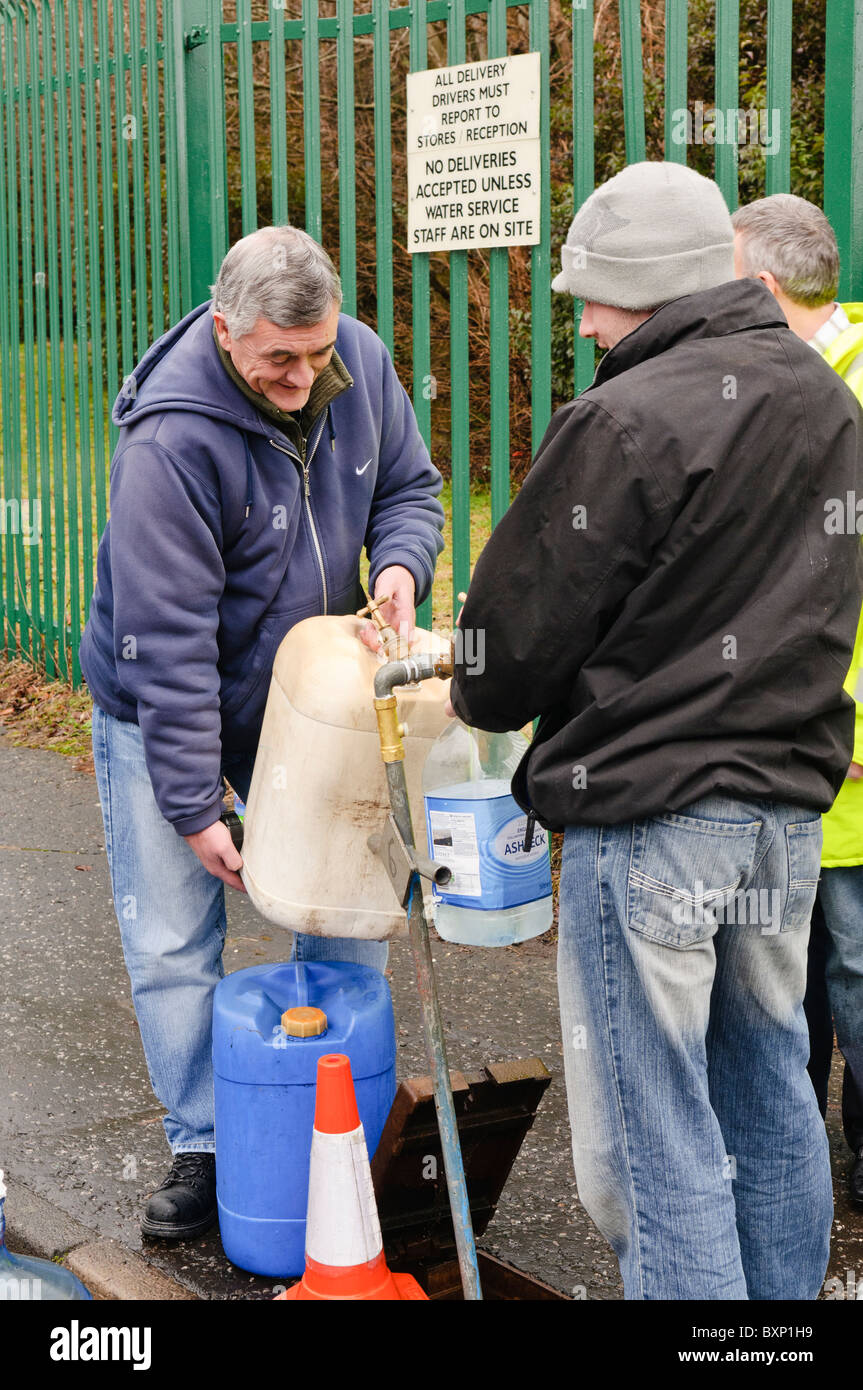 People fill plastic containers using a standpipe during a water ...