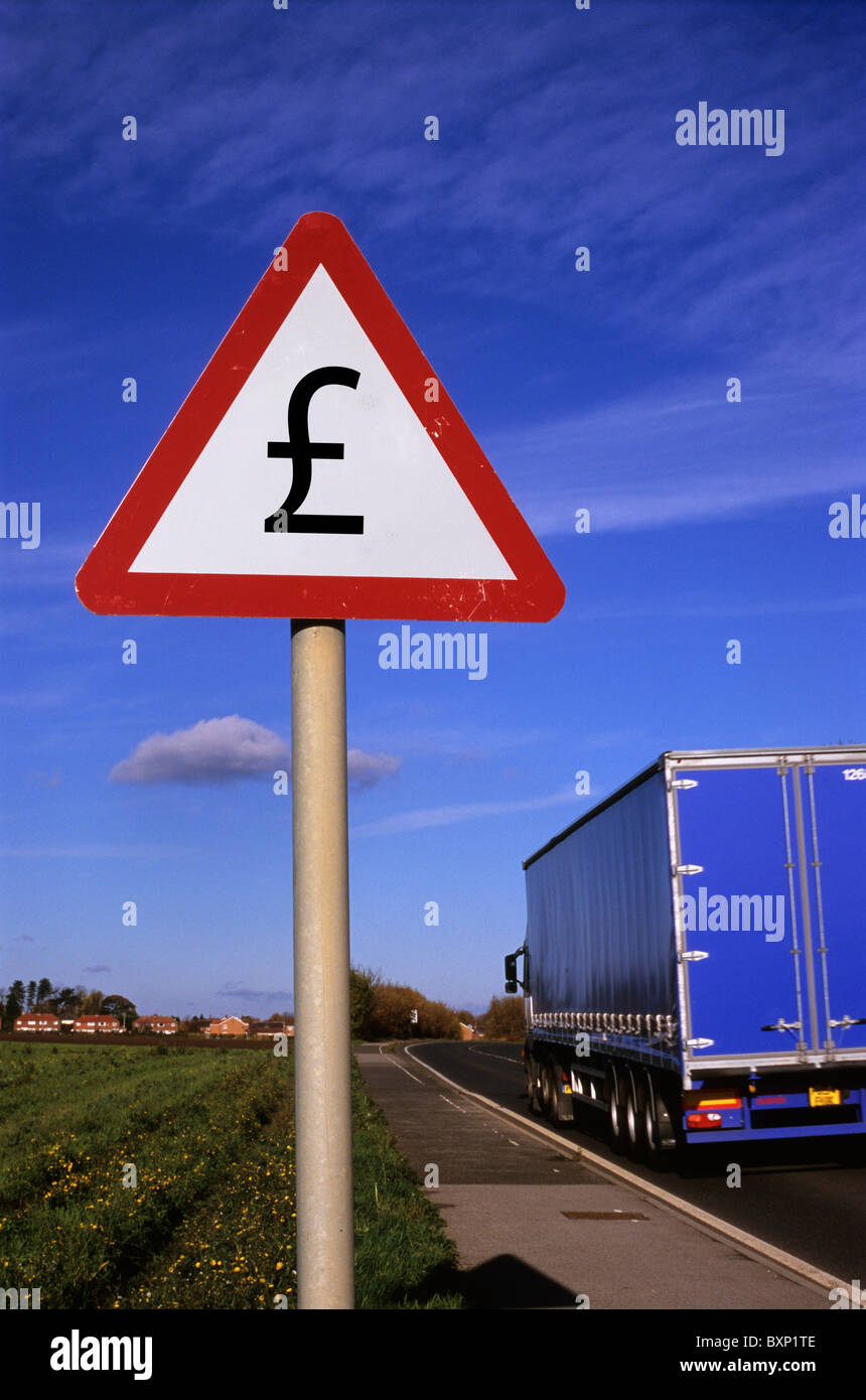 conceptual image of articulated lorry passing roadsign showing uk pound ...