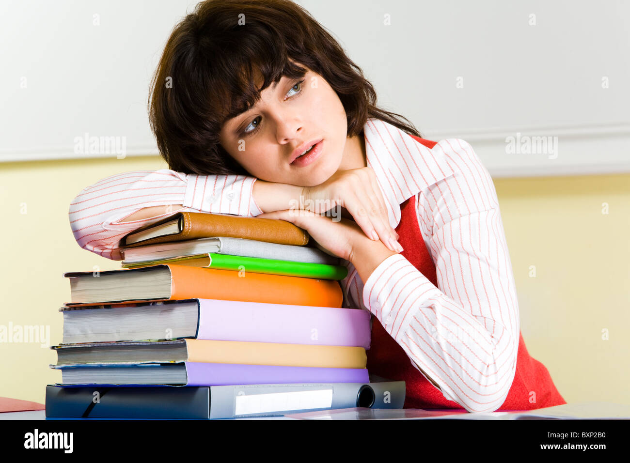 Photo of attractive woman putting her head onto stack of books and ...