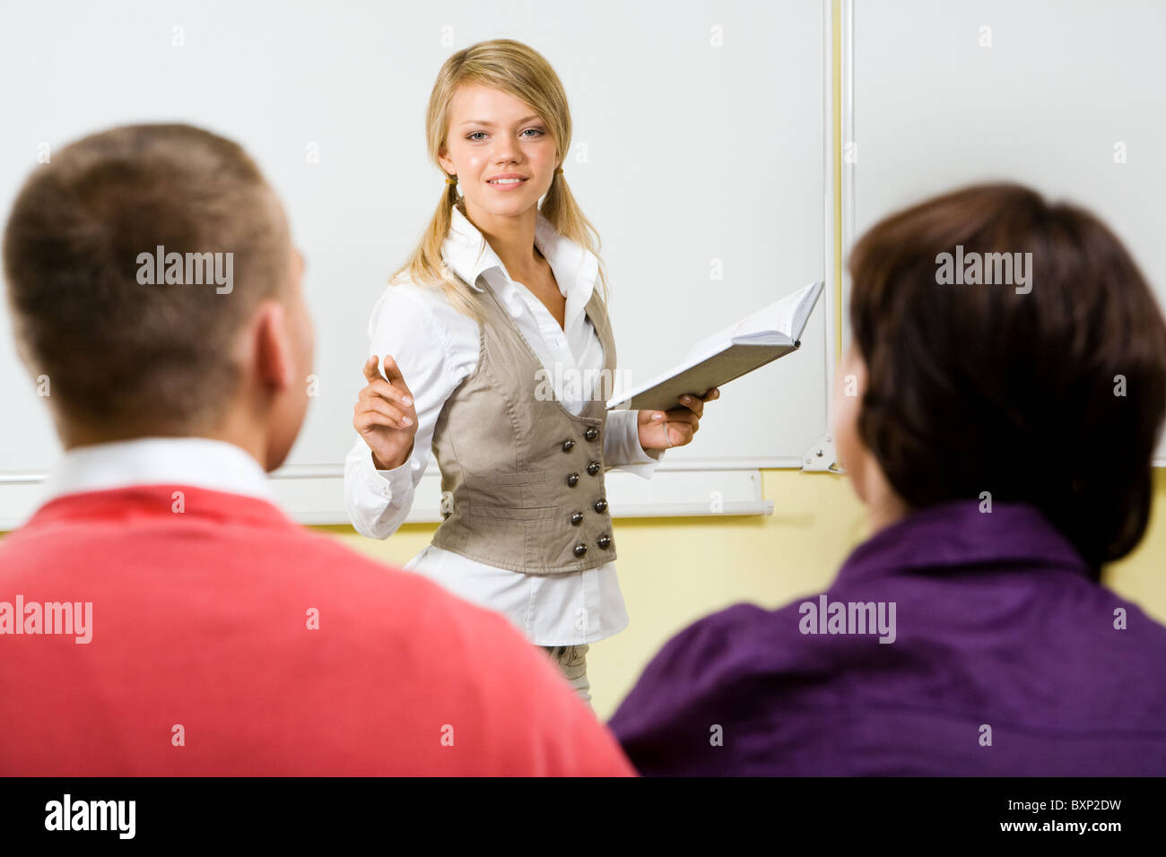 Image of clever teacher with book in hand explaining something to the ...
