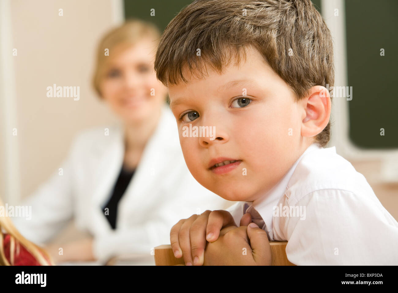 Face of clever schoolboy looking at camera in classroom with his ...