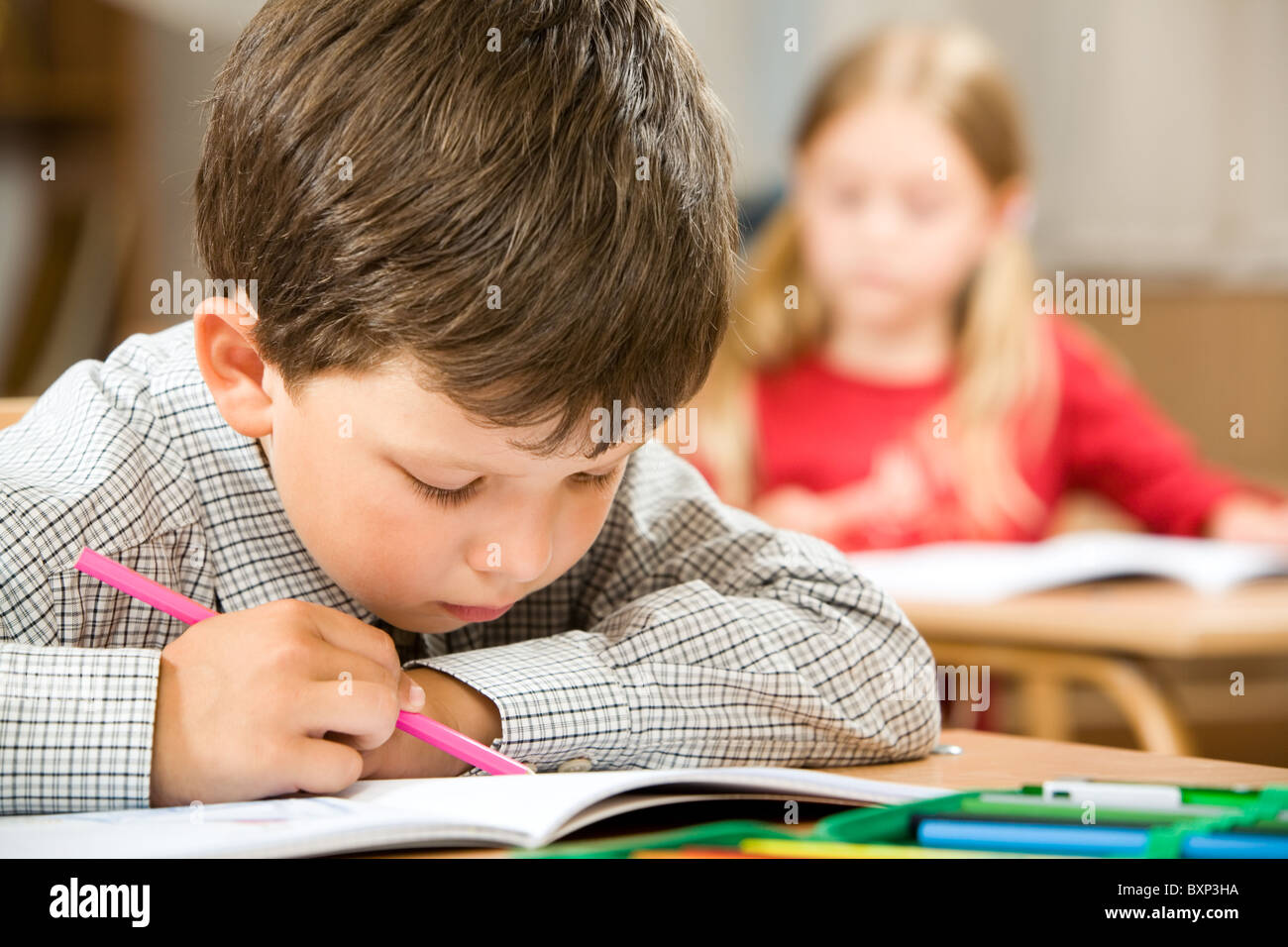 Photo of clever schoolkid writing something in his copybook at lesson ...