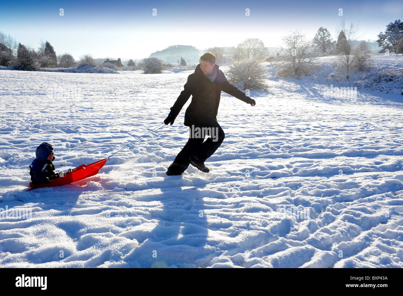 Father pulling son on sledge in winter snow England Uk Stock Photo - Alamy