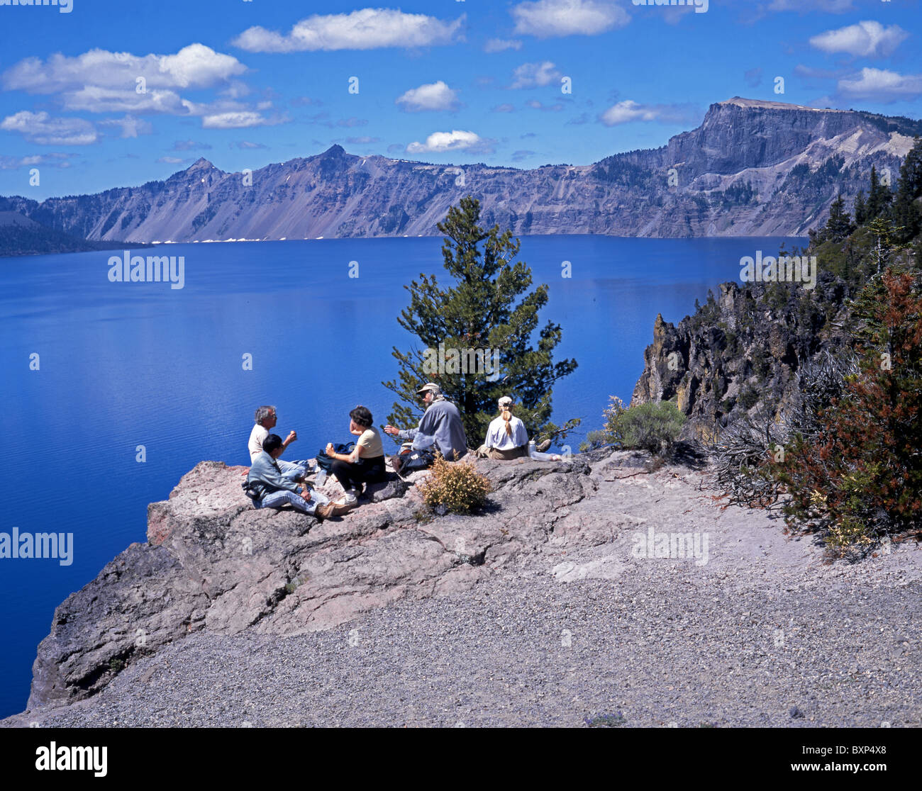 Lake view with people high up on rock at edge of lake having a picnic ...