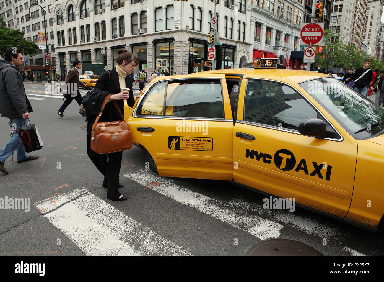A woman with a bag and a coffee cup getting into a taxi, New York City ...