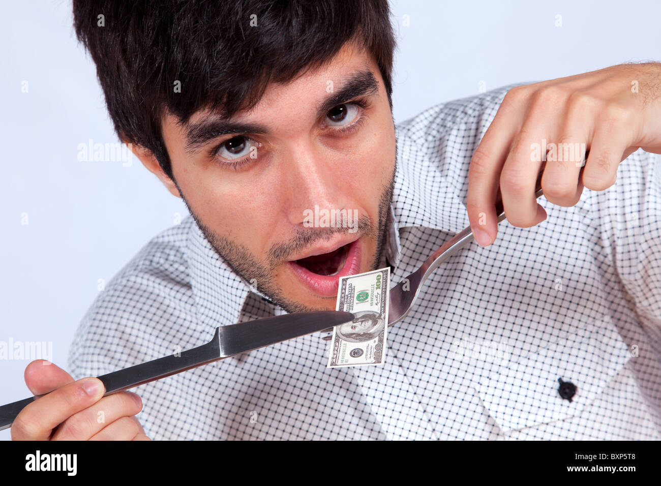 Man eating money with a fork and a knife Stock Photo - Alamy