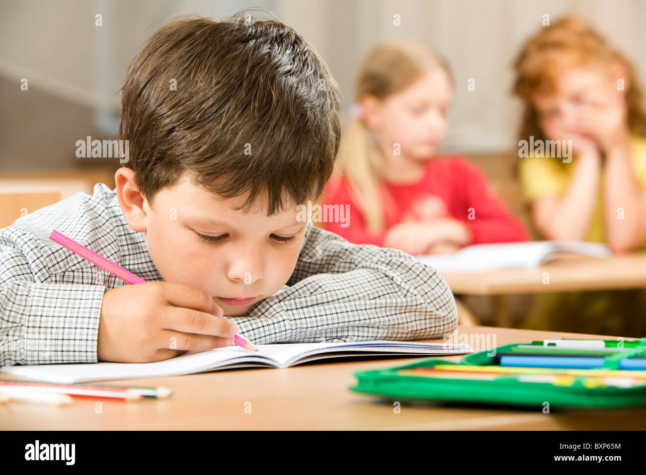 Portrait of bored pupil putting his head on desk and drawing something ...