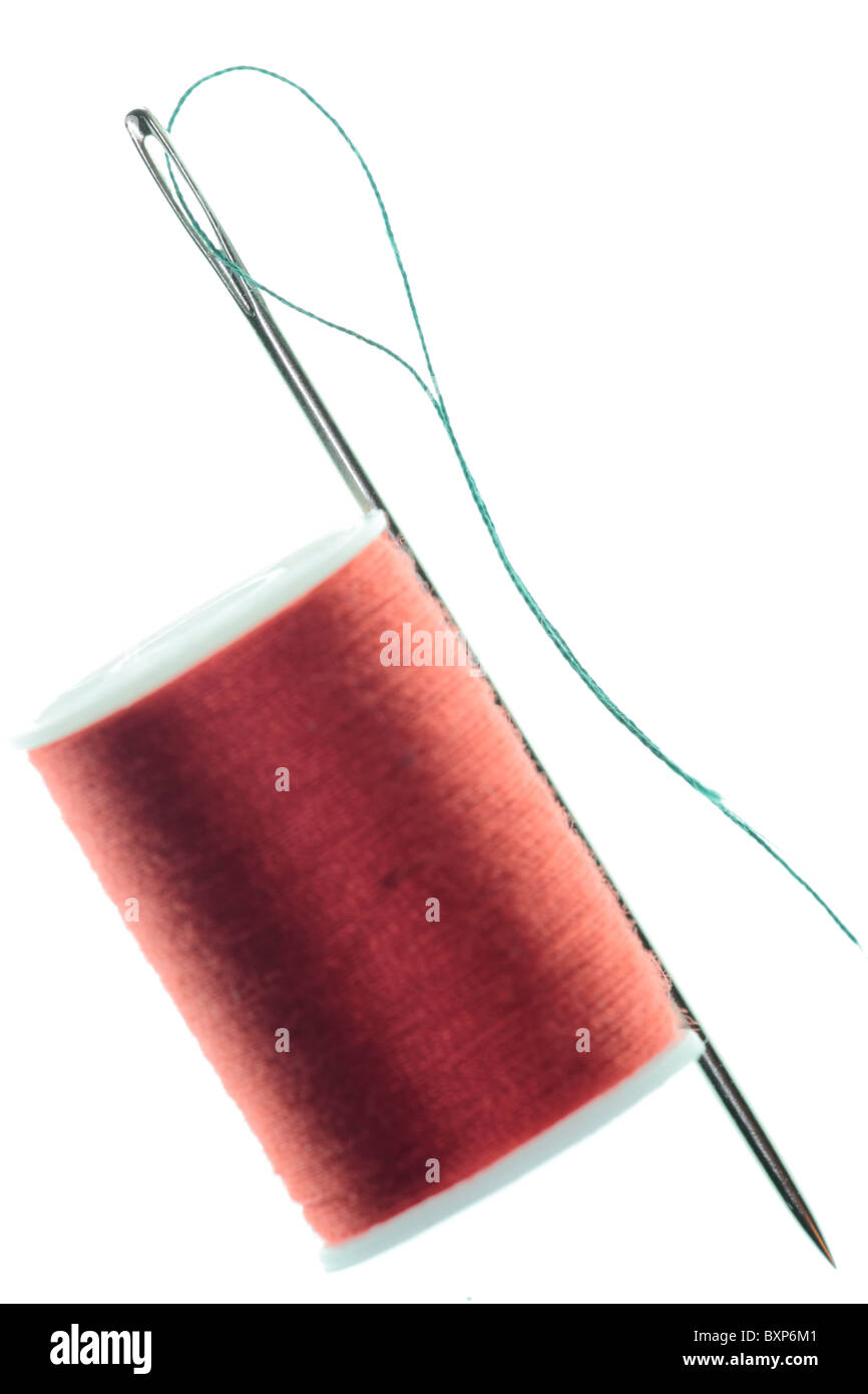 Red cotton reel with threaded needle Stock Photo - Alamy