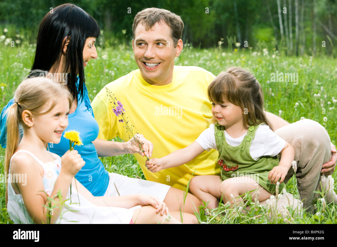 Portrait of little girl giving flower to her mother with father and ...