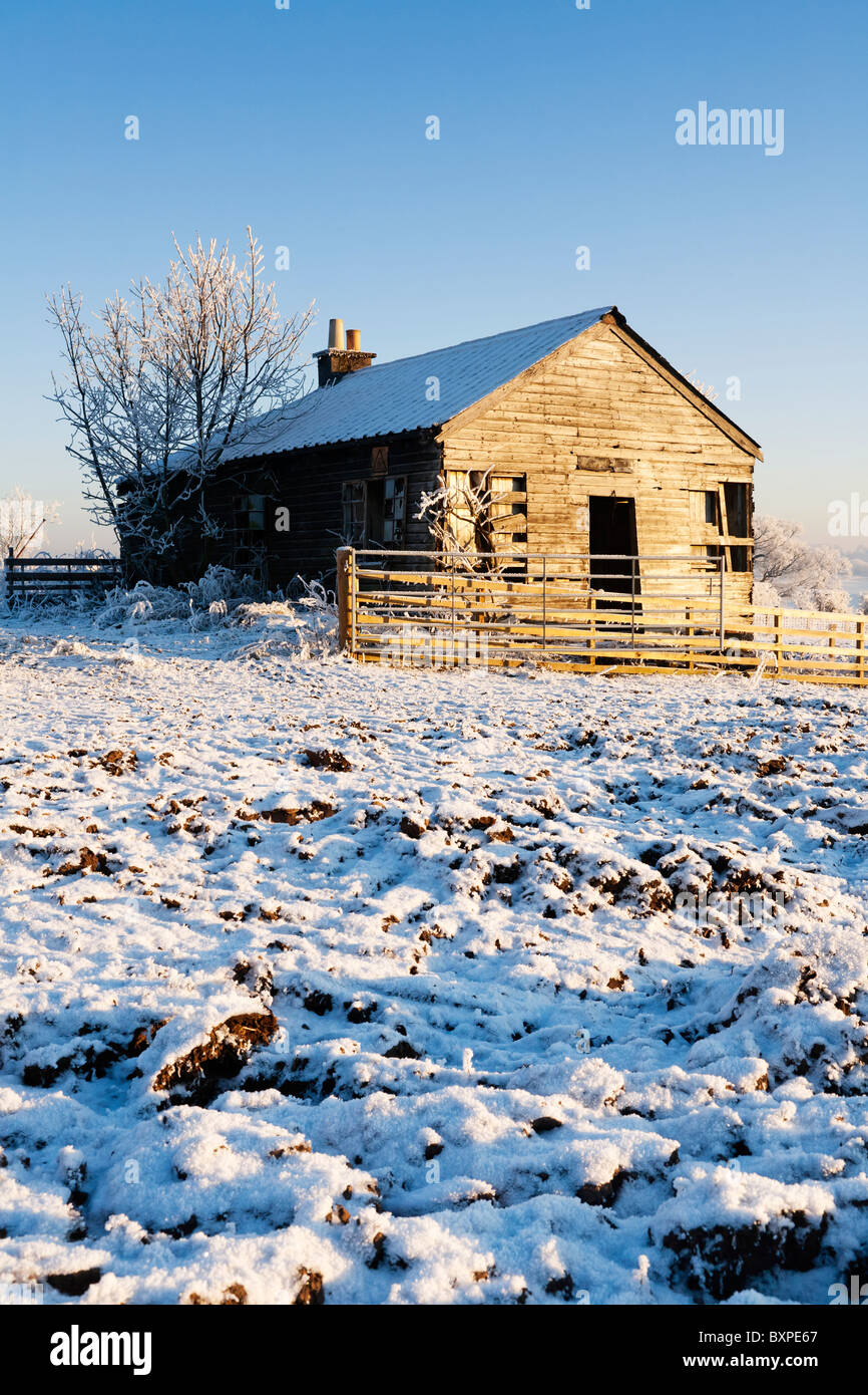 An old isolated run down wooden cottage in a snow covered Winter field ...